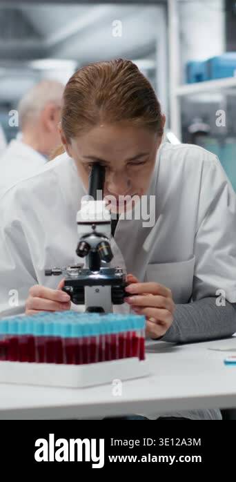 Vertical video Clinical microbiologist using compound microscope for ...