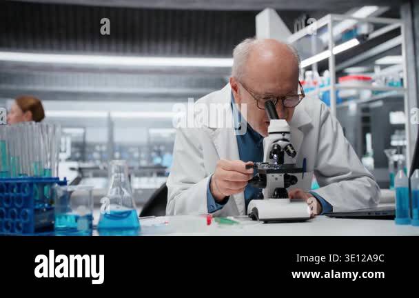 Laboratory materials scientist examining biopsy slide with microscope ...