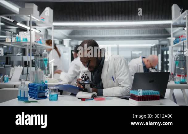 Lab researcher looking through scientific microscope lens to study ...