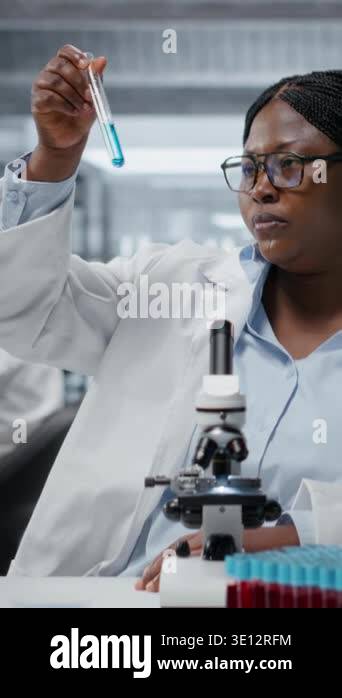 Vertical video Lab materials scientist investigating blue liquid ...