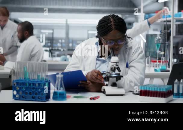 Female scientist using optical microscope to study microorganisms in ...