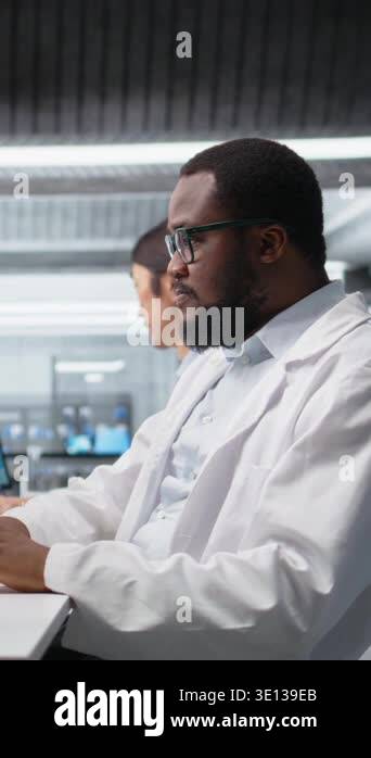 Vertical video Confused laboratory scientist frowning while looking at ...