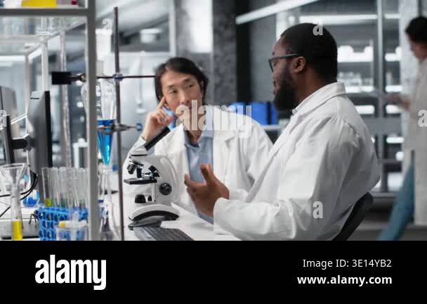 Diagnostic laboratory colleagues using microscope to evaluate cellular ...