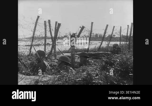 EUROPE - 1918 - Soldiers with bayonets hide in trench behind a barbed ...
