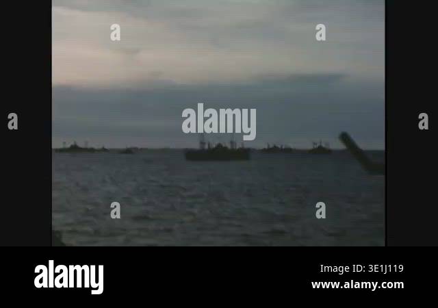 PACIFIC OCEAN - 1945 - A convoy of ships approaches the harbor beneath ...