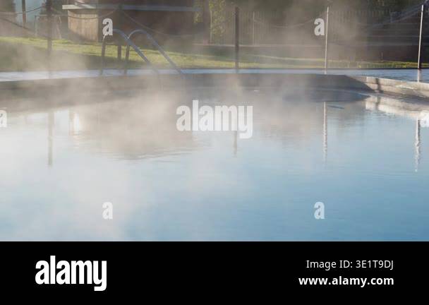 Serene view of a steaming outdoor swimming pool in the morning. Hot ...