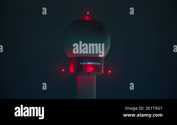 Static close-up shot of an airport radar tower at night. The radome and ...