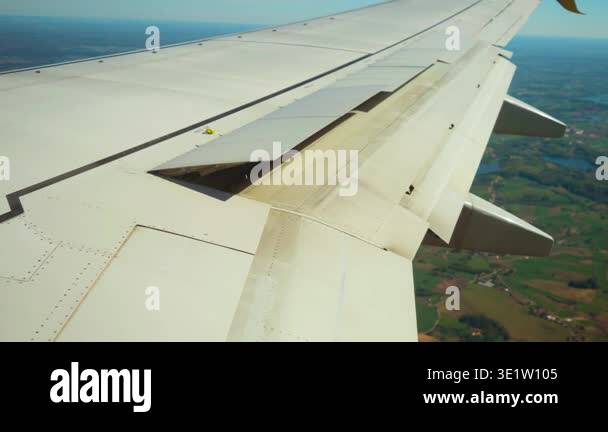 Jet landing above green landscape, extending flaps on wing. Plane ...