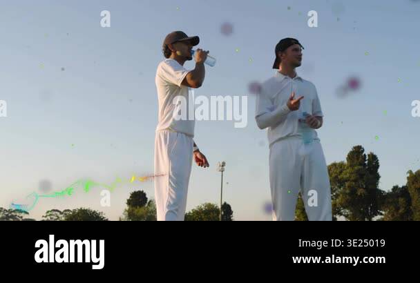 Two athletes on sports field for hydration, left drinking from bottle ...