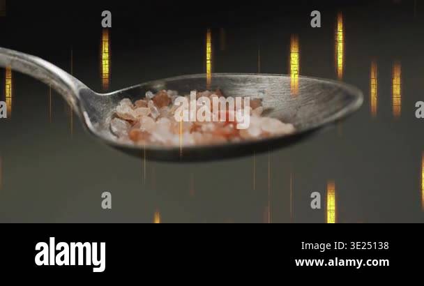 Gold streaks appearing salt grains falling into metal spoon hitting ...