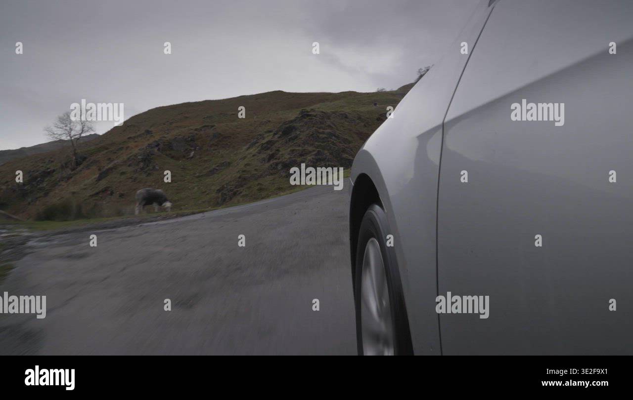 Car driving up a steep and narrow mountain road. Cumbria, UK Stock ...