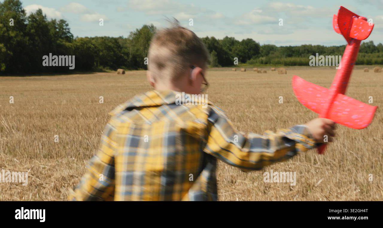 Cheerful boy playing on meadow and launching toy airplane Stock Video ...