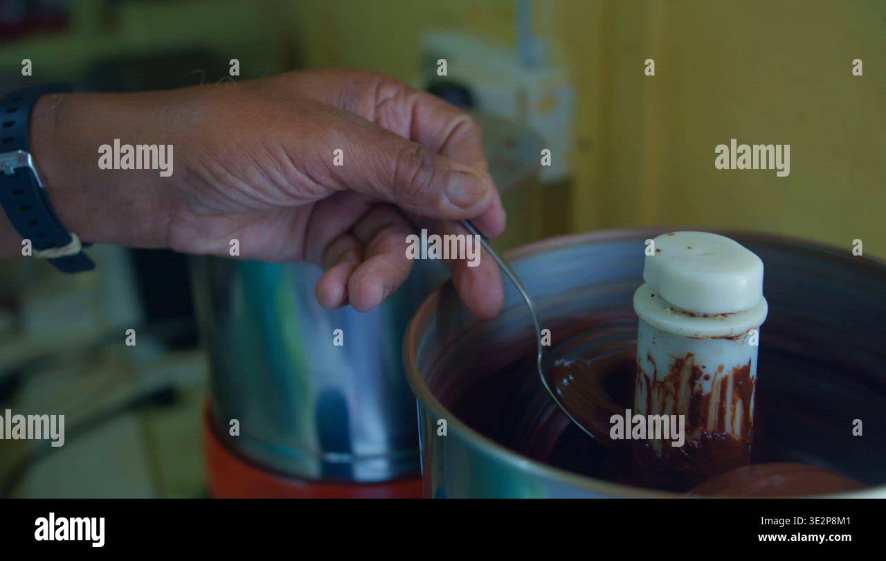 A man lifting a spoon of molten chocolate while making chocolate Stock ...