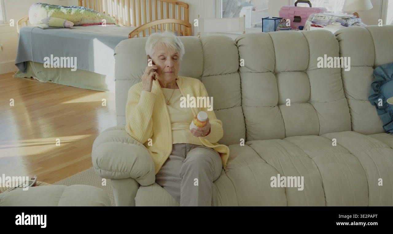 Senior Citizen on couch with prescription pill drug pill on phone Stock ...