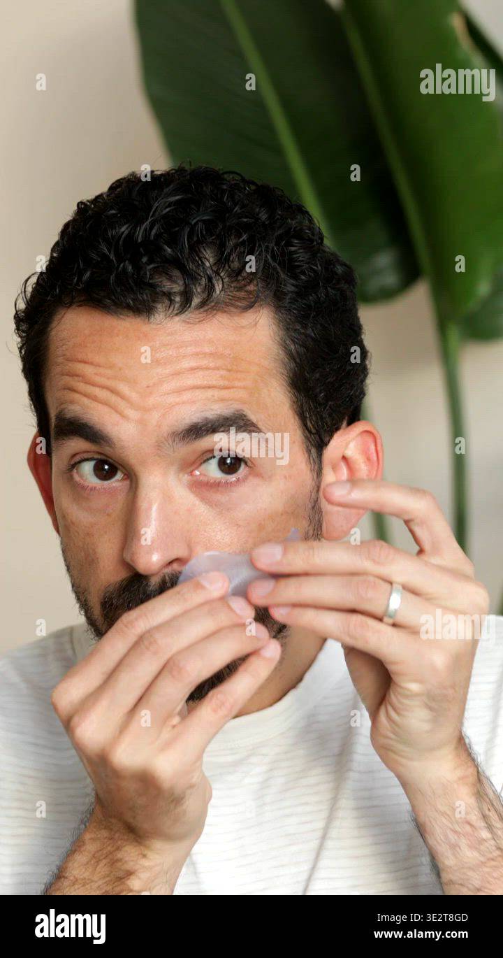 A man with a mustache applies an anti-wrinkle patch under his eyes ...