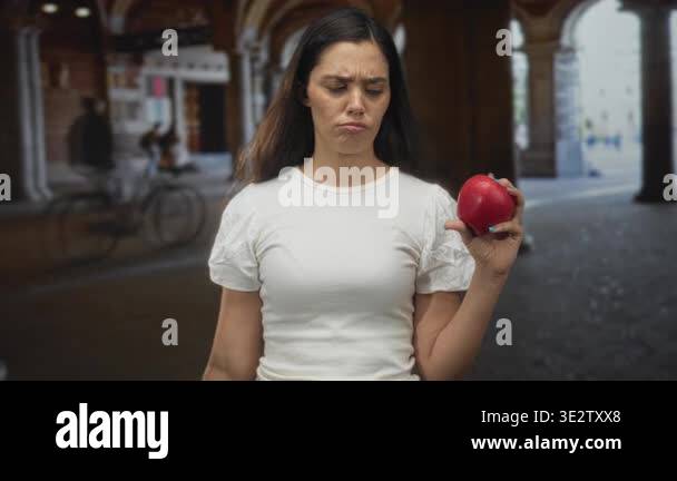 Woman holds shiny red apple with extended right hand near brick ...
