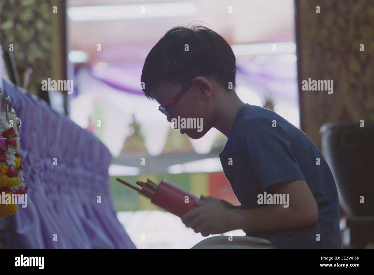 6K open gate(3:2) footage of boy shaking kau cim sticks in Thai temple ...