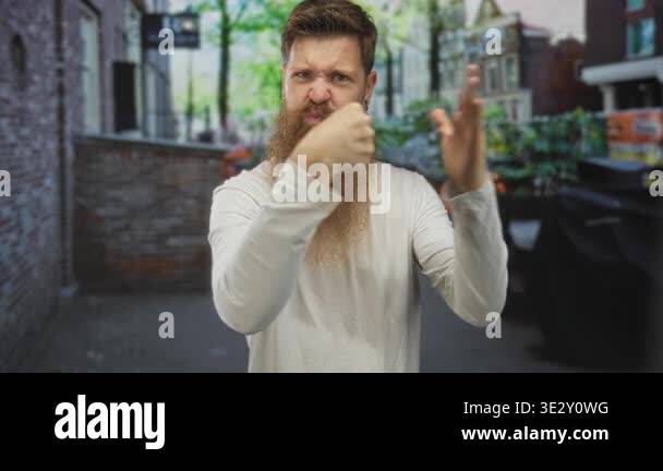 Young caucasian man with beard throws a punch with fist in boxing ...