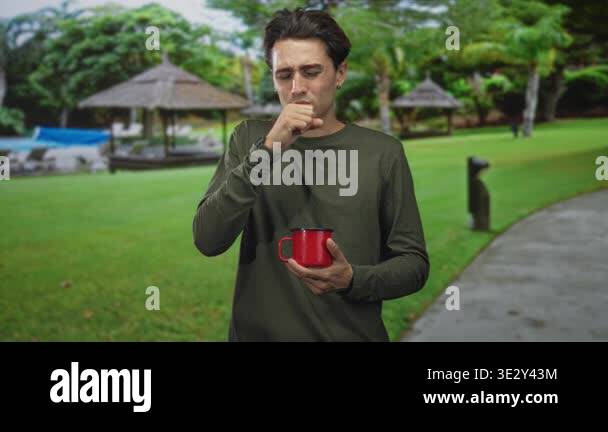 Man holding red mug and pressing forehead while covering eyes in a ...