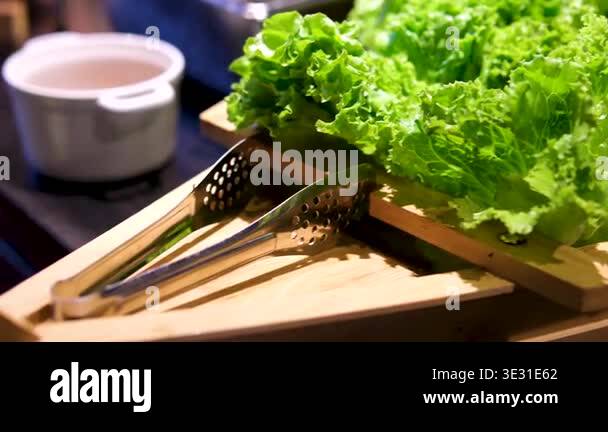 lettuce leaves at a restaurant buffet using tongs to serve fresh salad ...