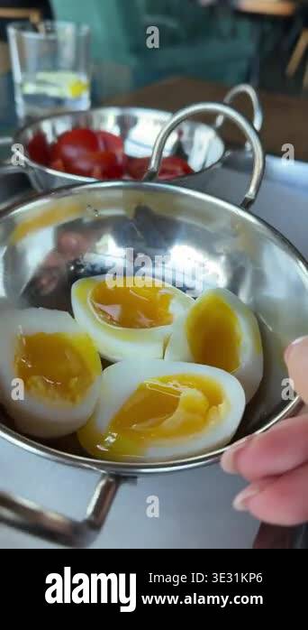 Close up of person holding soft-boiled egg with runny yolk partially ...
