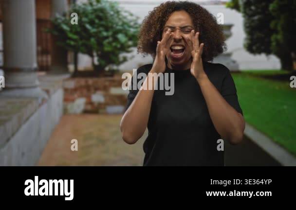 Woman cupping hands around mouth shouting in front of stone building ...