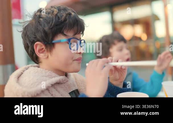 Young boy wearing eyeglasses drinking a soda from a paper cup with a ...