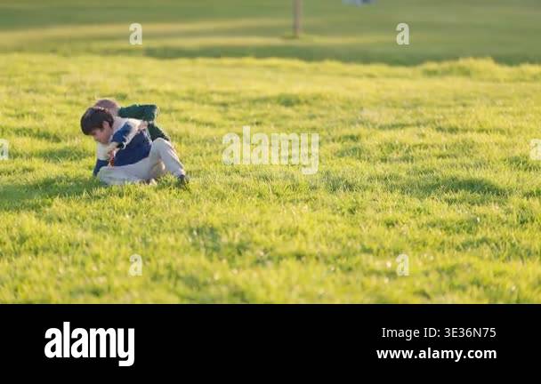 Two young brothers playfully fighting and wrestling together on a sunny ...