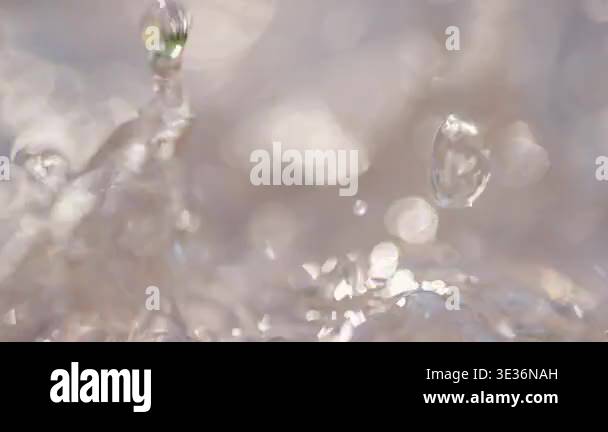 Extreme close-up of water drops falling into a puddle with sparkling ...