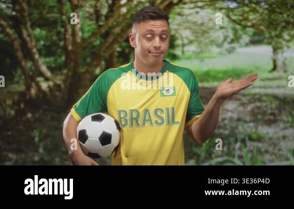Man holding soccer ball with palm up shrug in forest wearing brasil ...