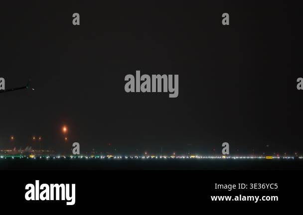 A passenger airplane makes a dramatic night landing on a brightly lit ...