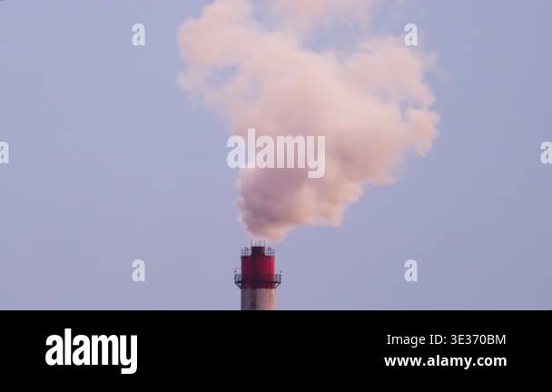 Industrial smokestack releasing thick smoke into the sky above a city ...
