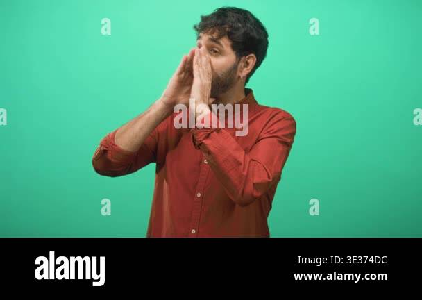 Man cupping hand to mouth and covering face, bearded young man in red ...