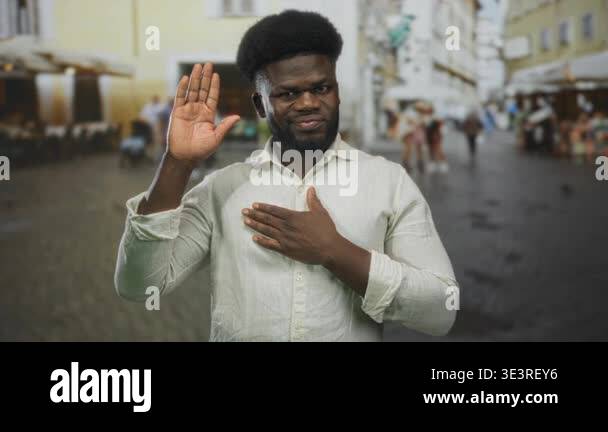 Man raising right hand with palm up and left hand on chest on crowded ...