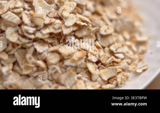 Dry rolled oat flakes piled inside bowl. Natural whole grain cereal ...
