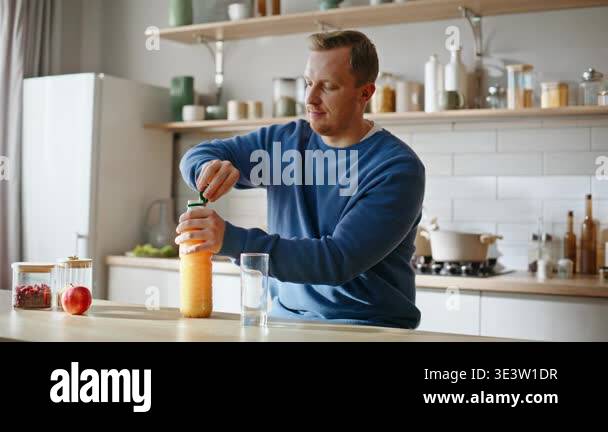 Carefree guy open juice bottle sitting modern kitchen closeup. Relaxed ...