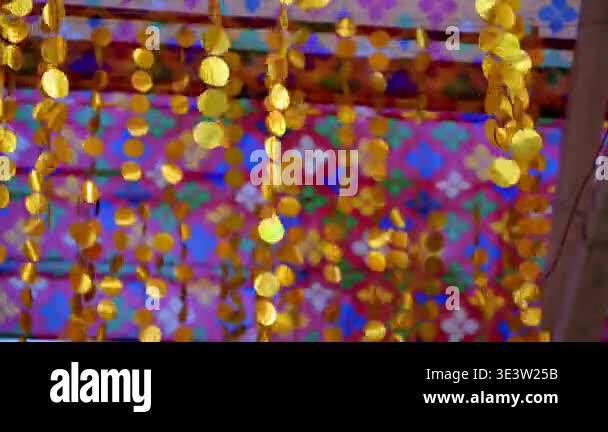 Close-up of shimmering golden hanging disc garlands swaying gently in ...