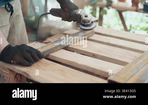 A worker is grinding rust off a steel part with an angle grinder. Close ...