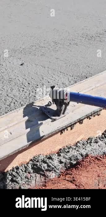 Construction worker uses leveling tool to smooth wet concrete on ...