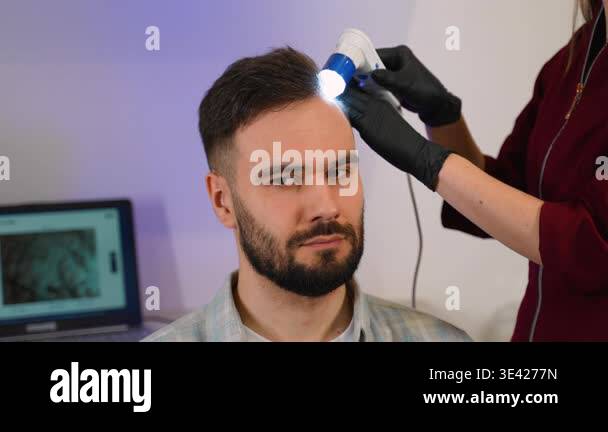 Professional trichologist using a digital dermatoscope to analyze the ...