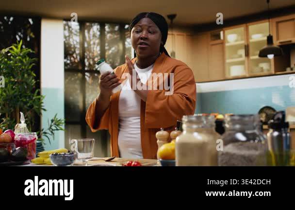 African American woman pouring yogurt in a bowl for breakfast idea with ...