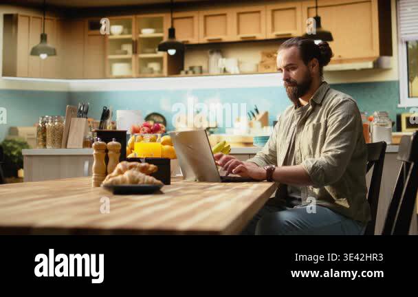 Unpunctual nervous man looking at time on wrist watch in the kitchen ...