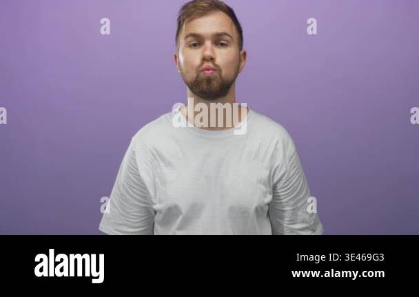 Man pointing index fingers and pursing lips in a studio with purple ...