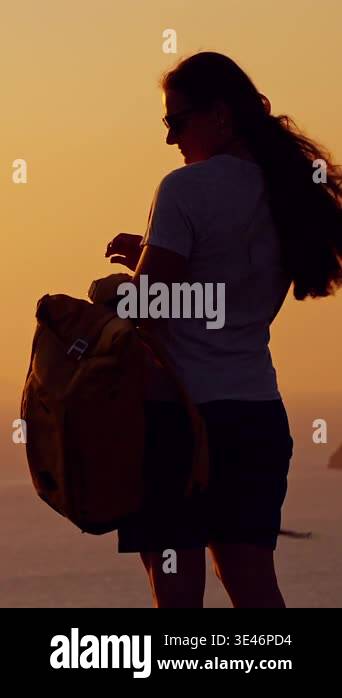 Vertical video. Side View Woman Removing Backpack at Cliff Edge During ...