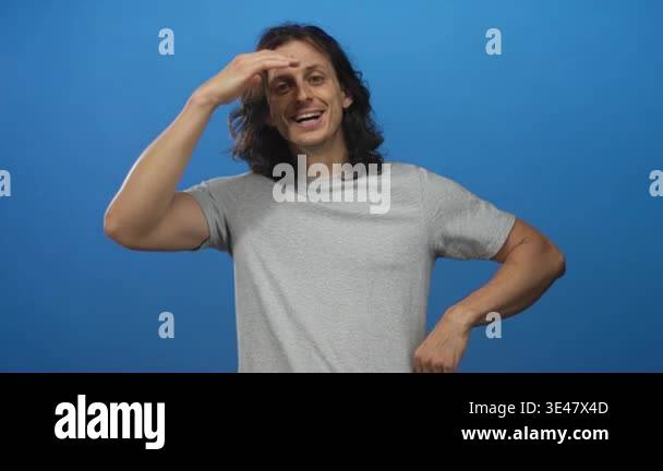 Man shielding eyes with hand to forehead and smiling face in a blue ...
