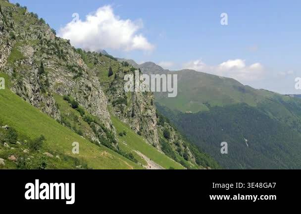 Steep rocky cliffs and lush green slopes under a partly cloudy sky in ...