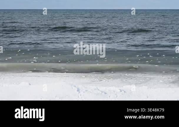 Chilly ocean water with small waves softly breaking on pristine snow ...