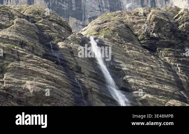 A narrow waterfall cascades down rugged rocky cliffs at the Cirque de ...