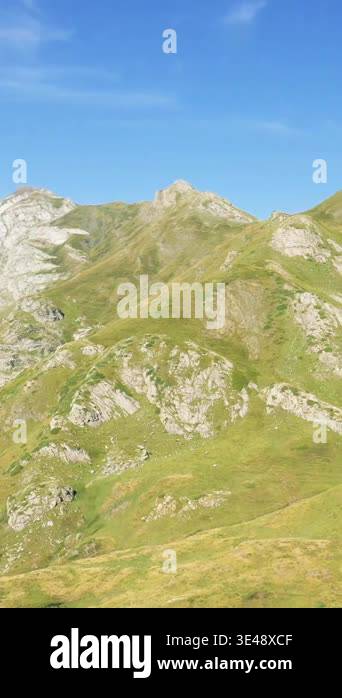 Green rocky slopes of the Pyrenees mountains under a clear blue sky on ...