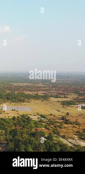 Wide aerial shot of rural fields, scattered trees, and a small pond in ...